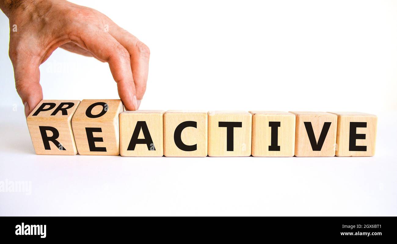 Symbole réactif ou proactif. Homme d'affaires tourne des cubes en bois ...