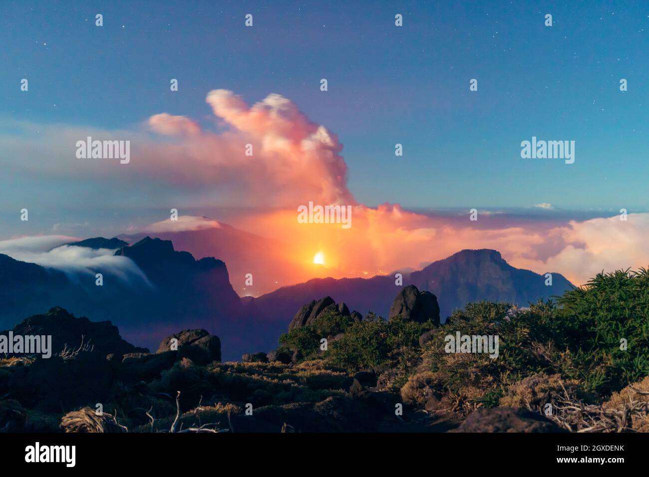 Paysage nocturne avec un volcan en éruption en arrière-plan et une mer ...