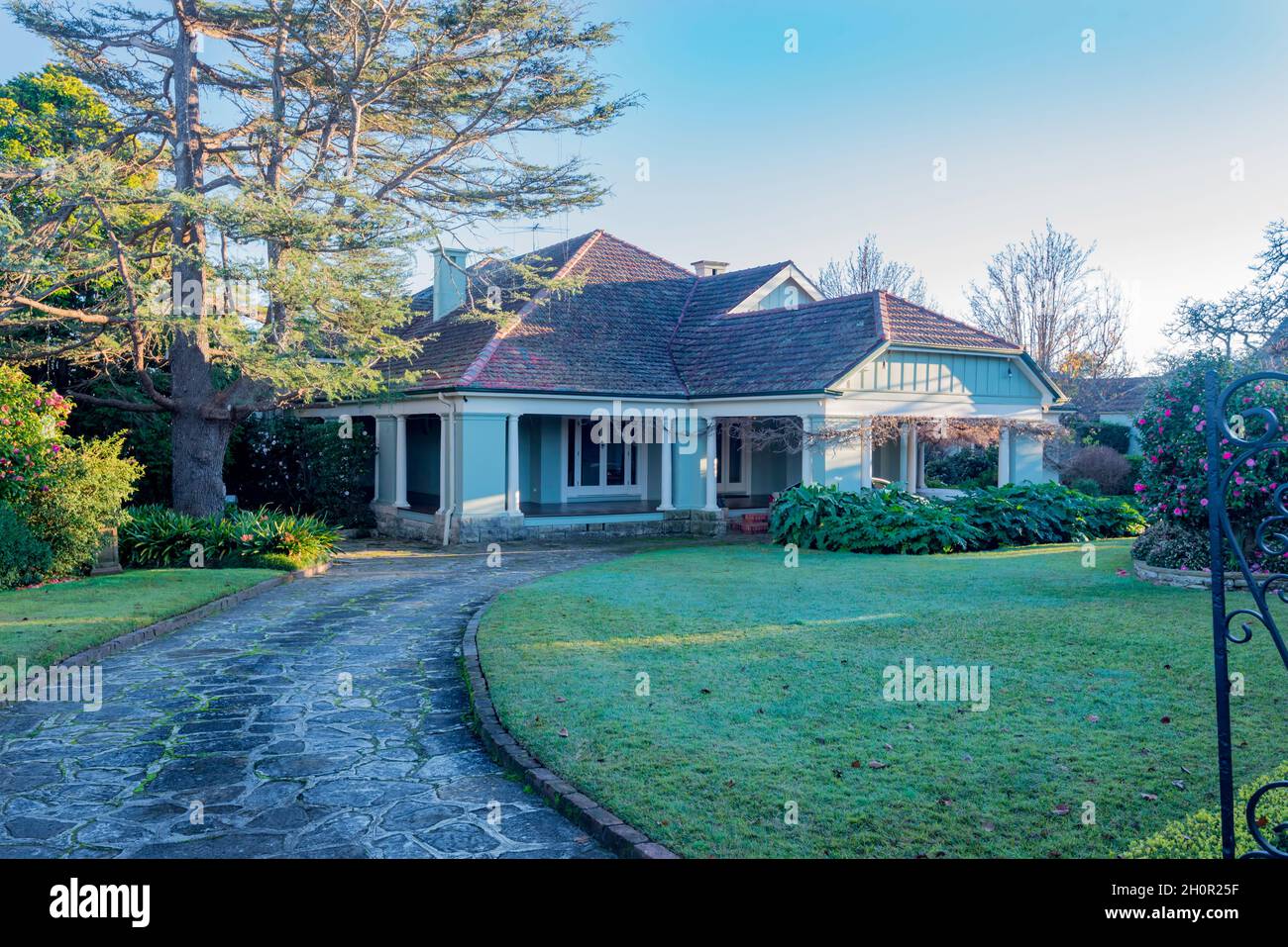 Une allée pavée circulaire en pierre mène sous une entrée portique ...