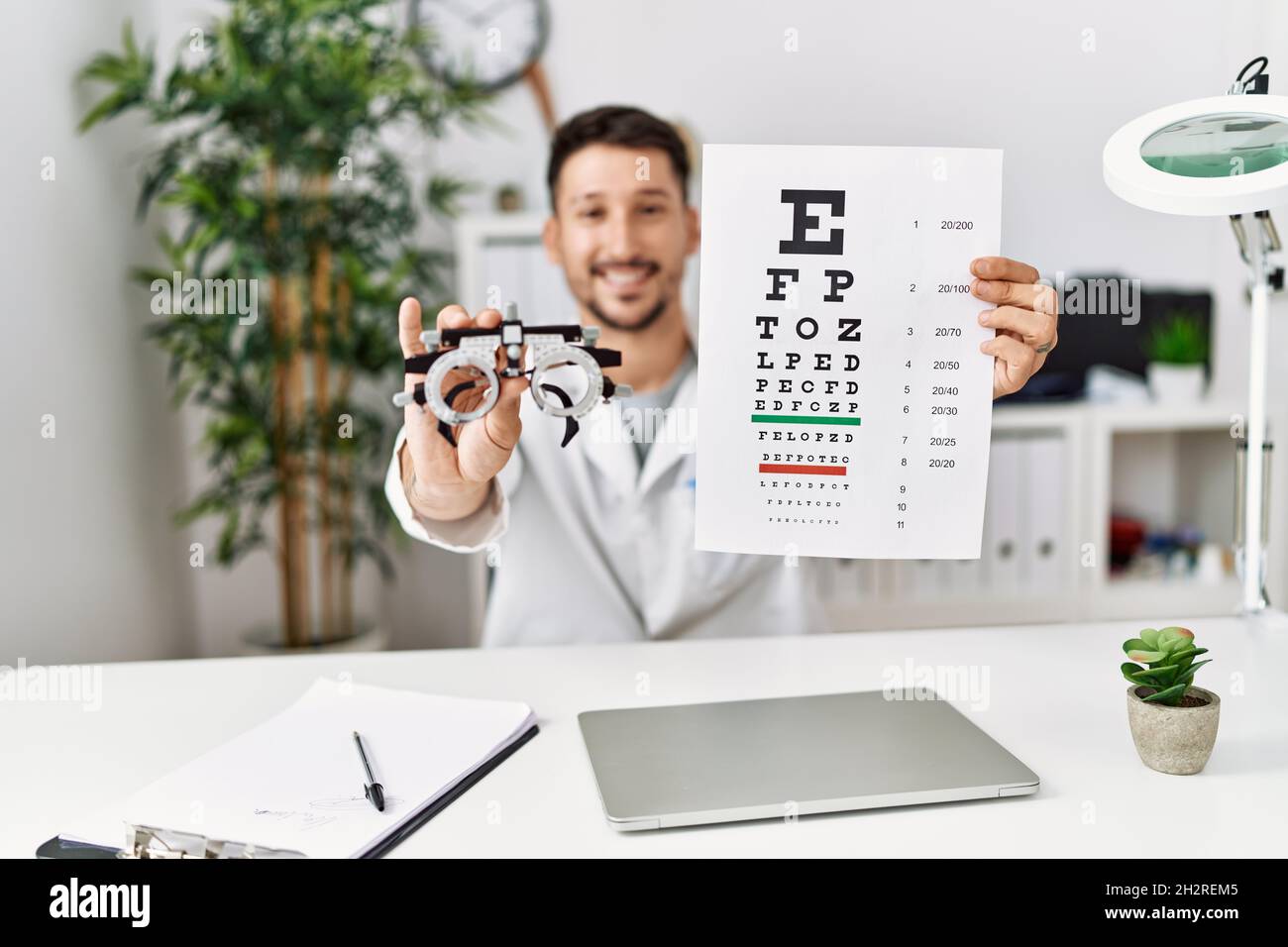 Jeune homme hispanique portant l'uniforme d'opticien, portant le test ...
