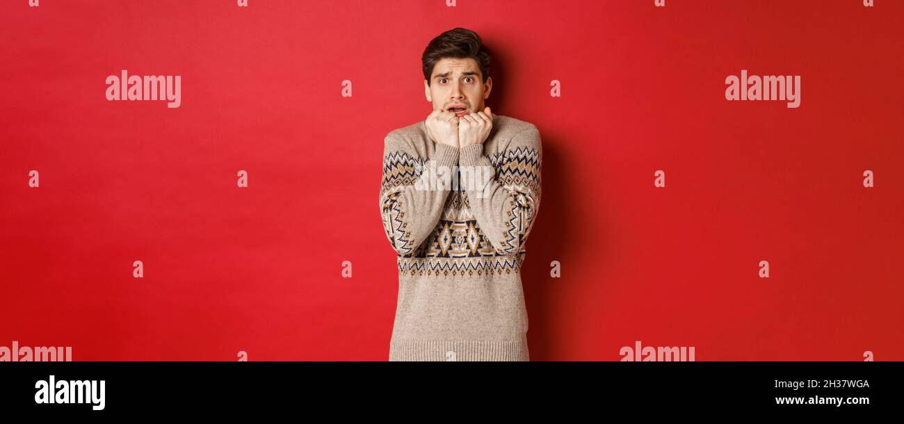 Portrait d'un homme effrayant et timide dans un chandail de noël, qui a ...