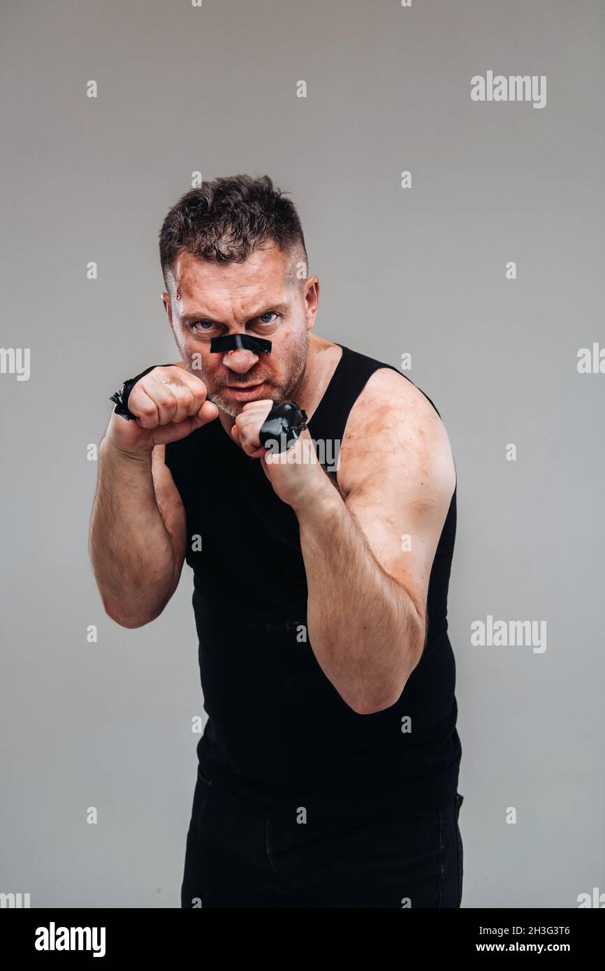 Sur fond gris se dresse un homme battu dans un T-shirt noir qui ...