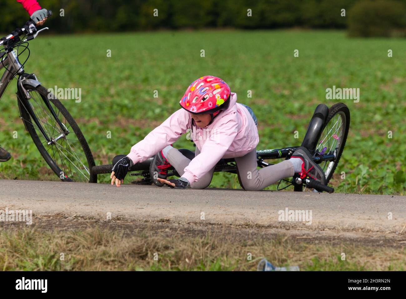 Enfant tombant de vélo, accident de rue, une fille avec un casque de ...