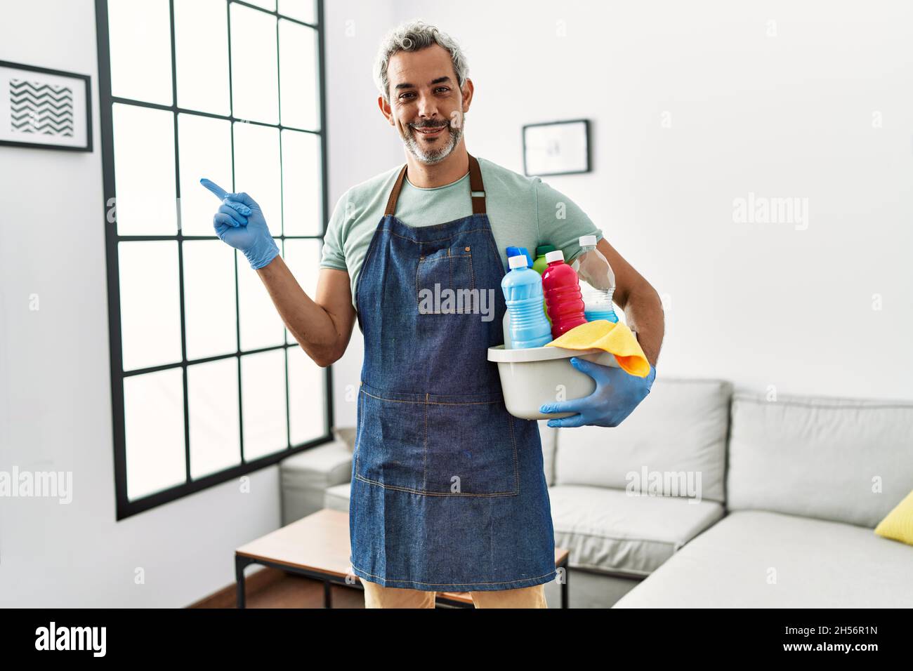 Homme hispanique d'âge moyen portant un tablier plus propre tenant les ...