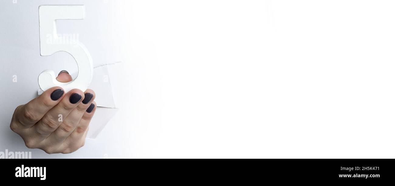 Main féminine tenant le numéro 5 sur fond blanc conceptuel des nombres ...