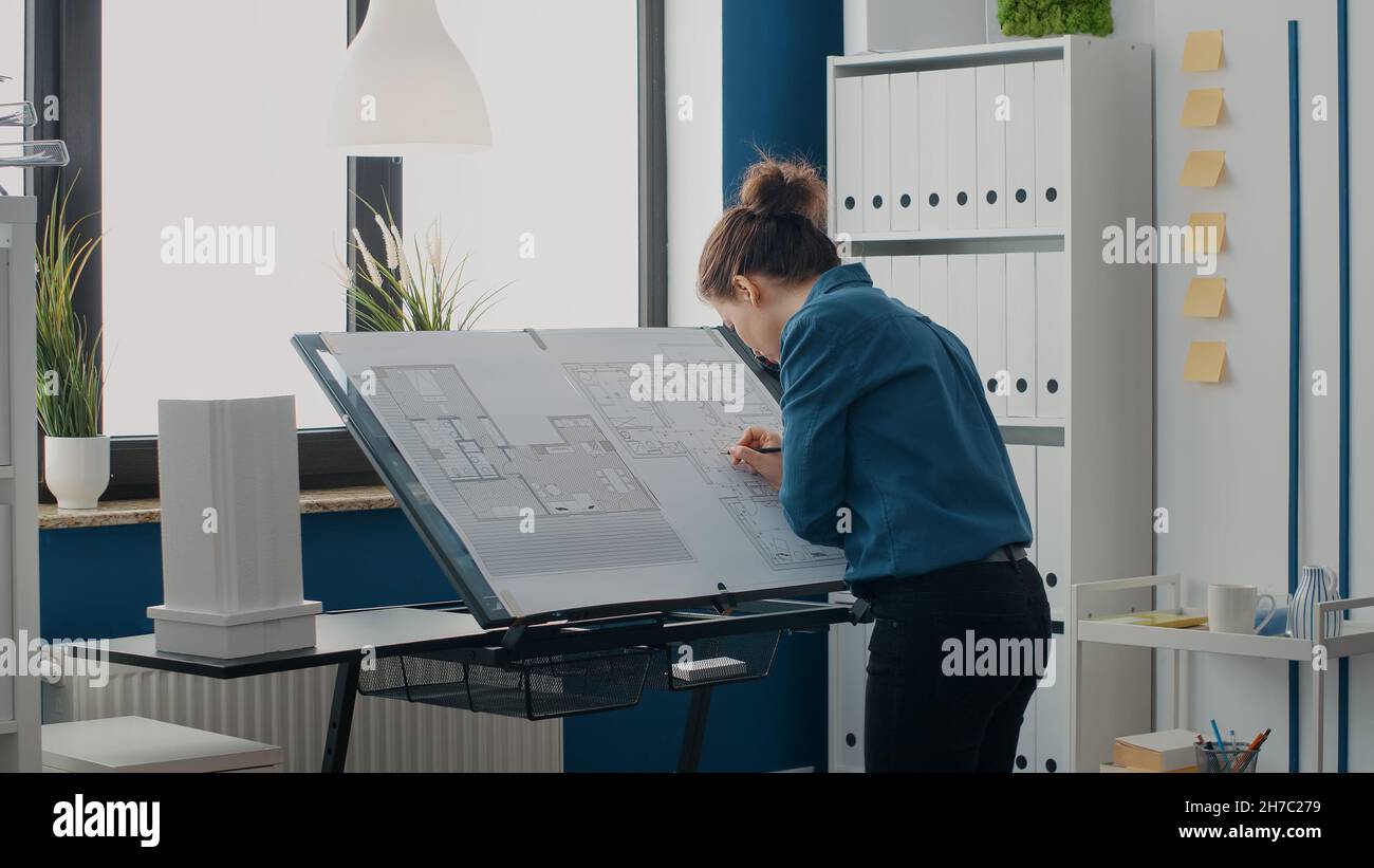 Gros plan d'une femme architecte prenant des notes sur les plans de ...