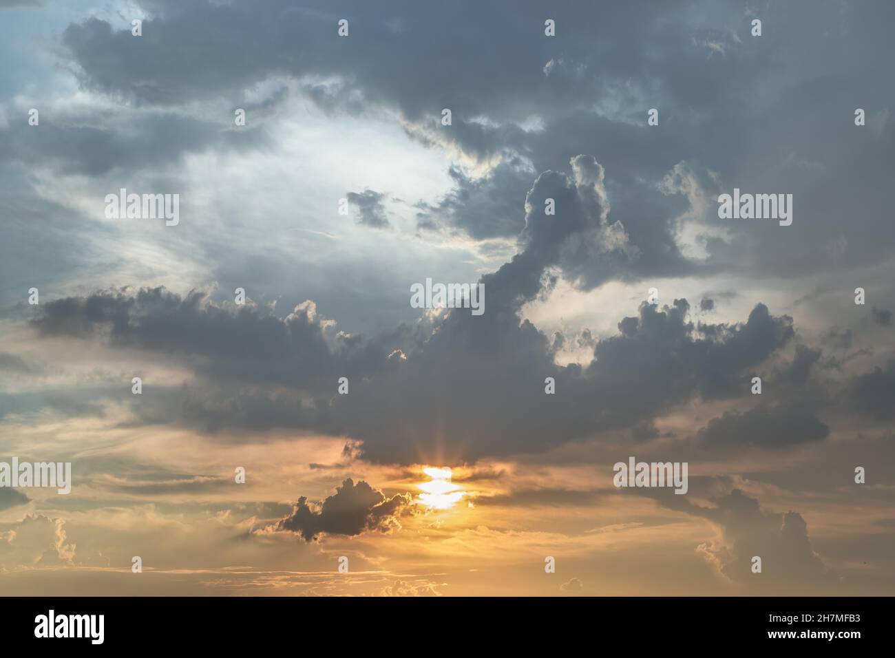 Le soleil brille à travers les nuages dans le ciel du coucher du soleil ...