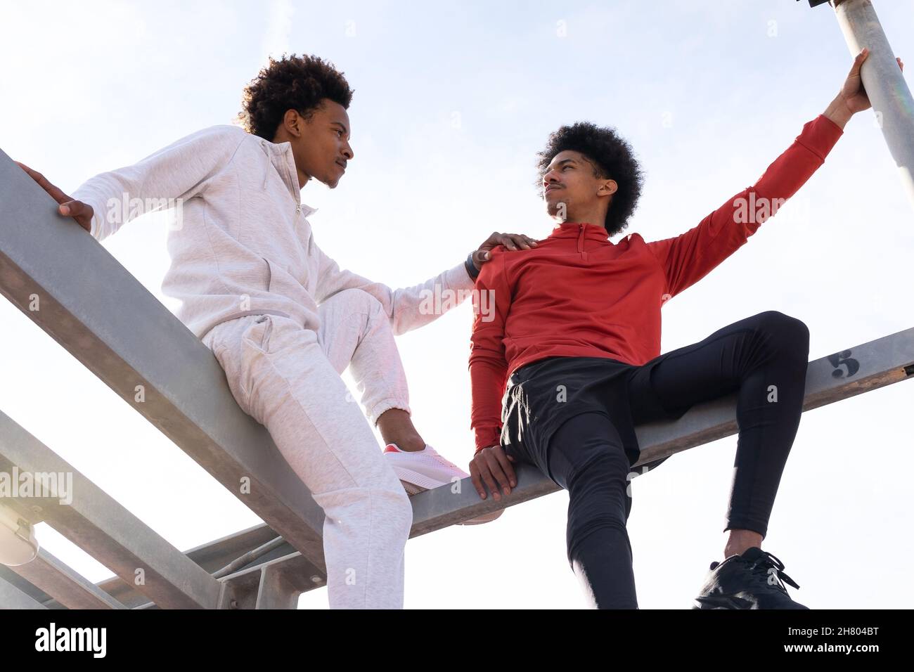 De dessous de l'homme afro-américain assis sur une poutre de fer ...