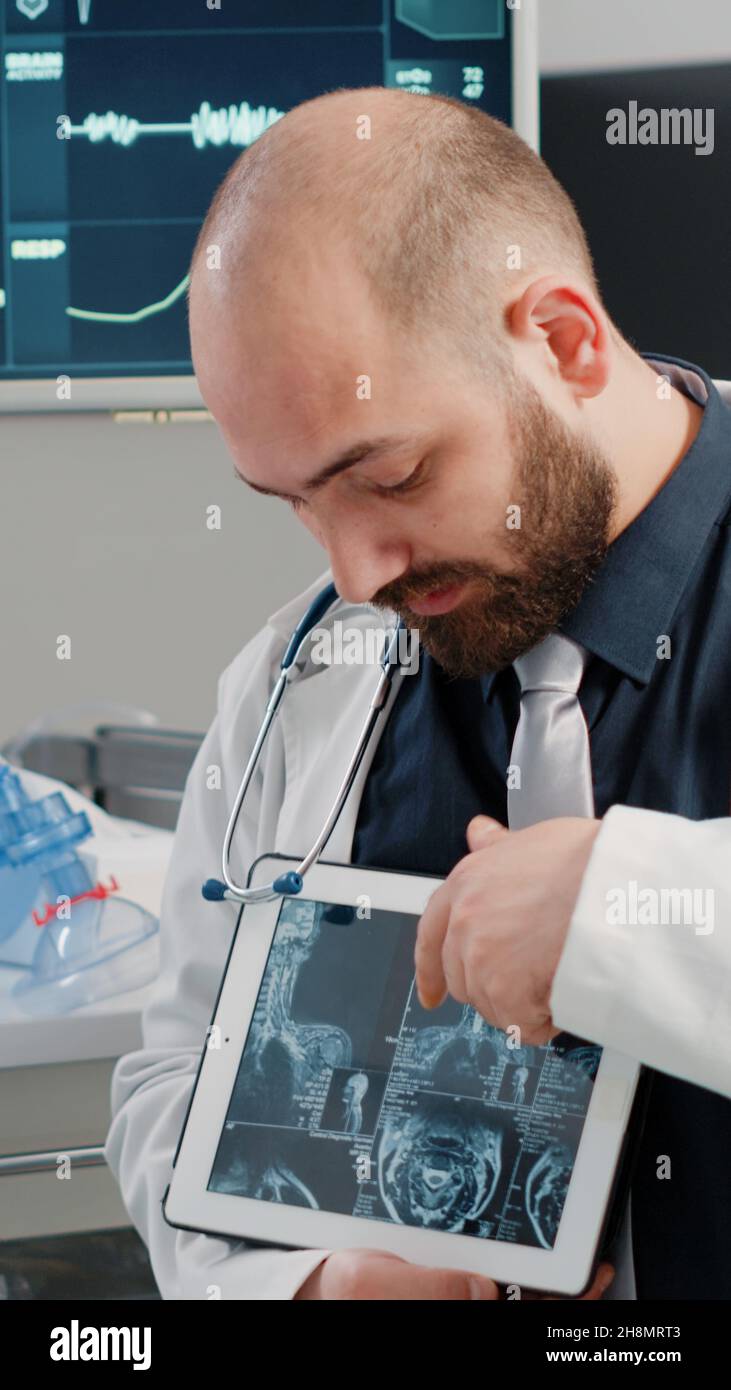 Gros plan du médecin tenant une tablette numérique avec radiographie pour les patients âgés ...