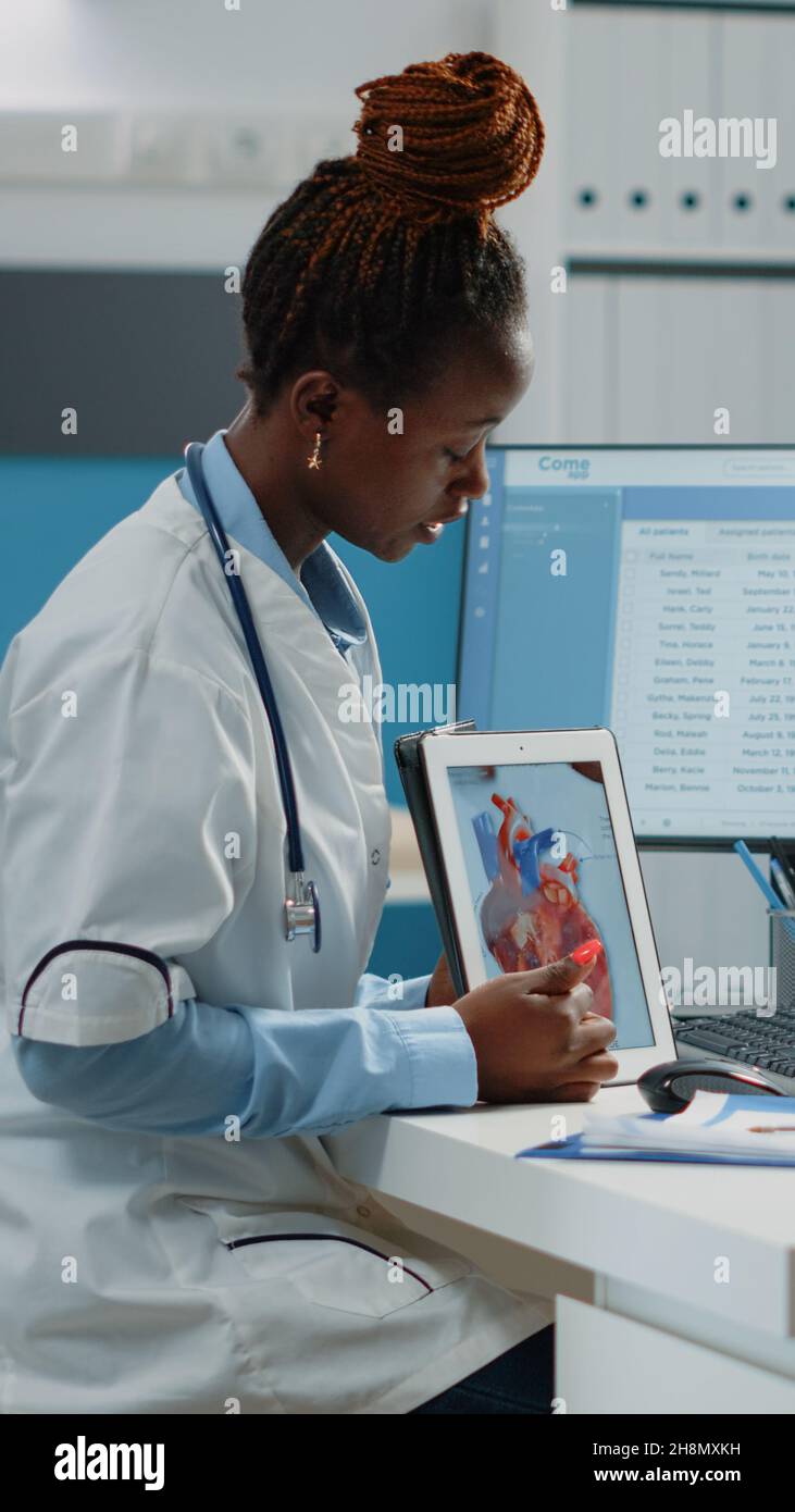 Médecin pointant vers une figure de cardiologie sur une tablette numérique pour expliquer le ...