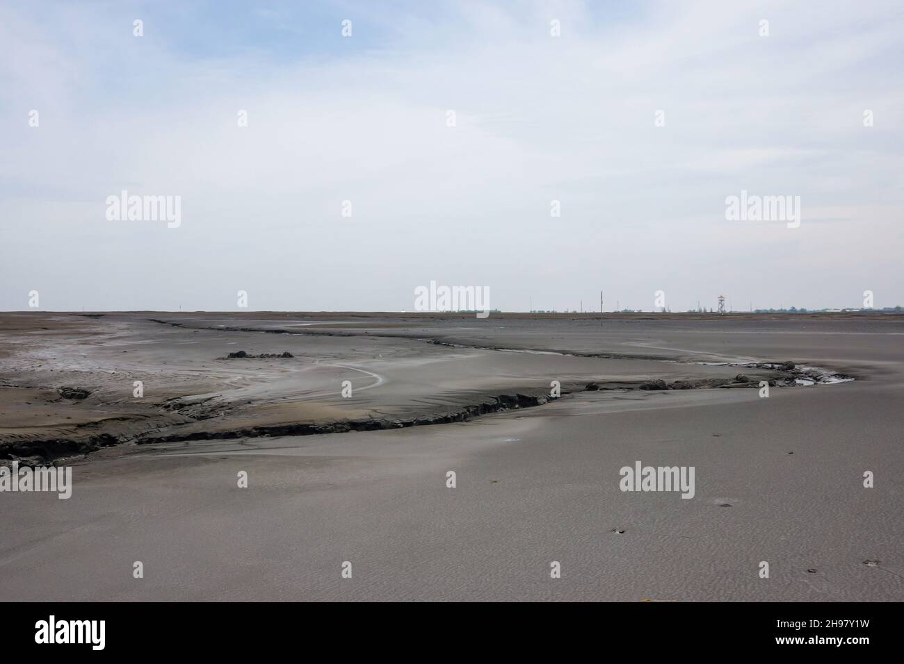 Lac de boue sèche formé d'une éruption de volcan de boue à Sidoarjo, Indonésie.Nuages dans le ...