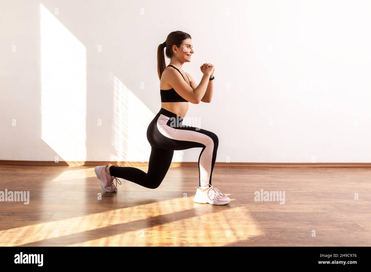 Femme mince faisant de l'exercice de fente de sport, debout un genou ...