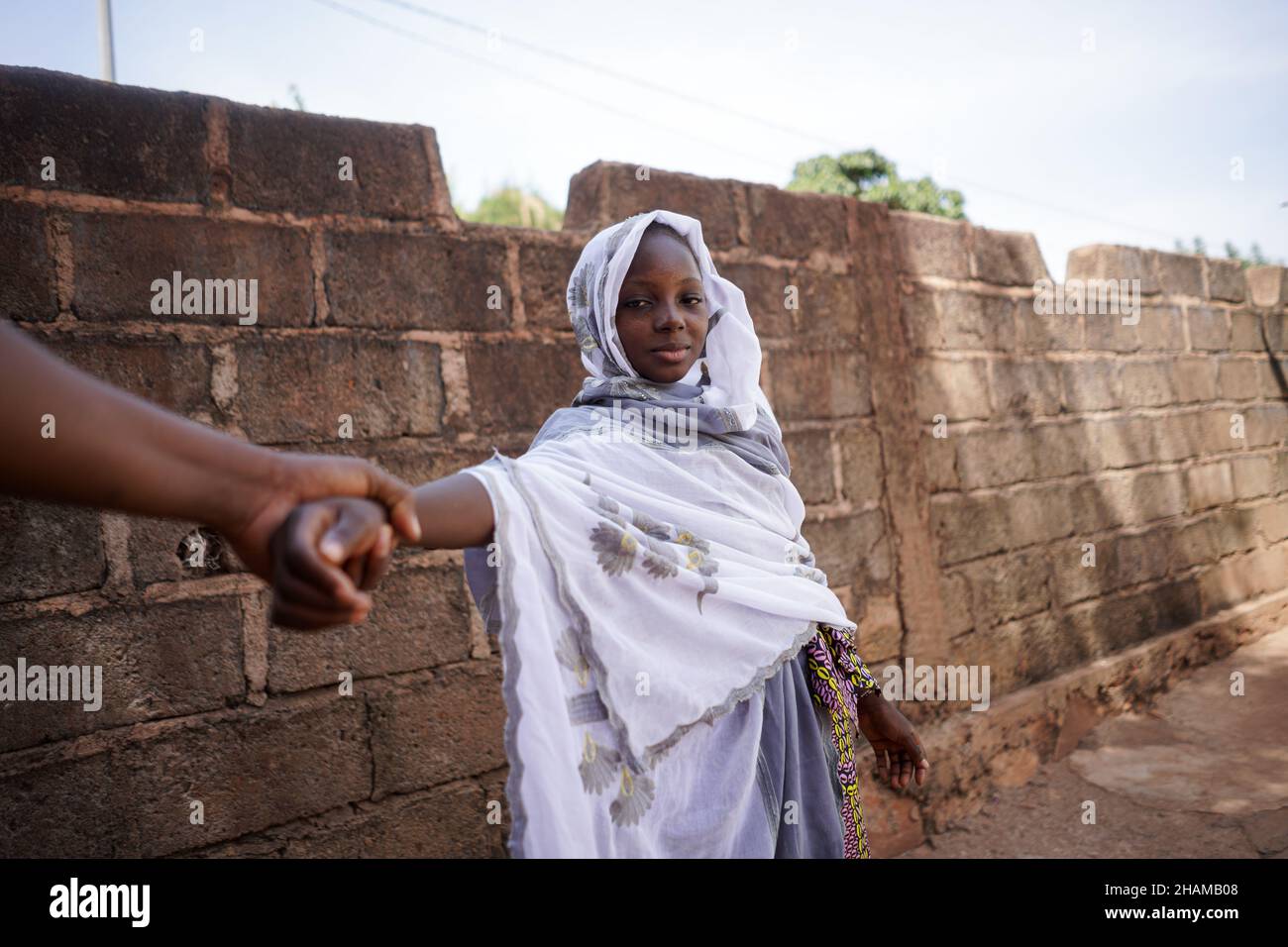 Une jeune fille malienne se tient et sourit dans une robe double ...
