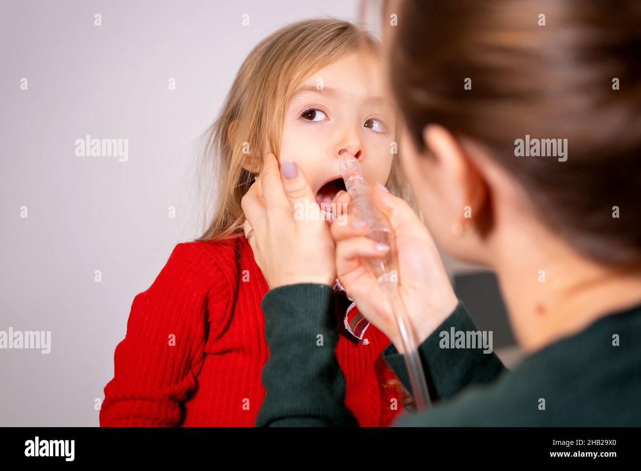 La mère rince le nez de sa petite fille avec un appareil d'inhalation ...