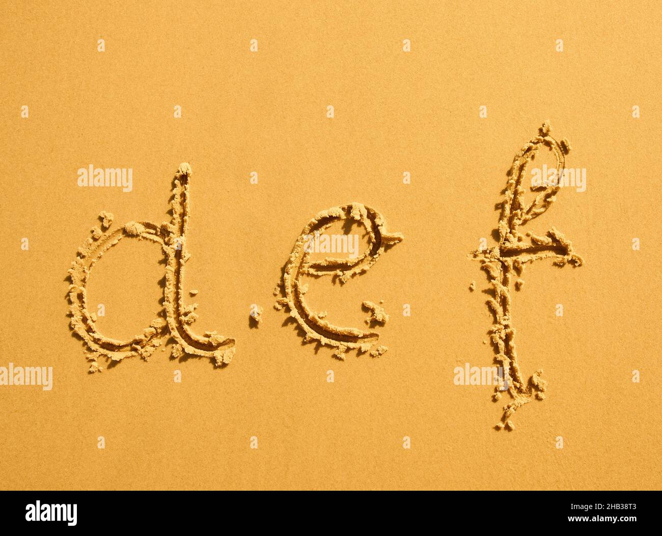 lettres de l'alphabet d e f manuscrites dans le sable sur la plage ...