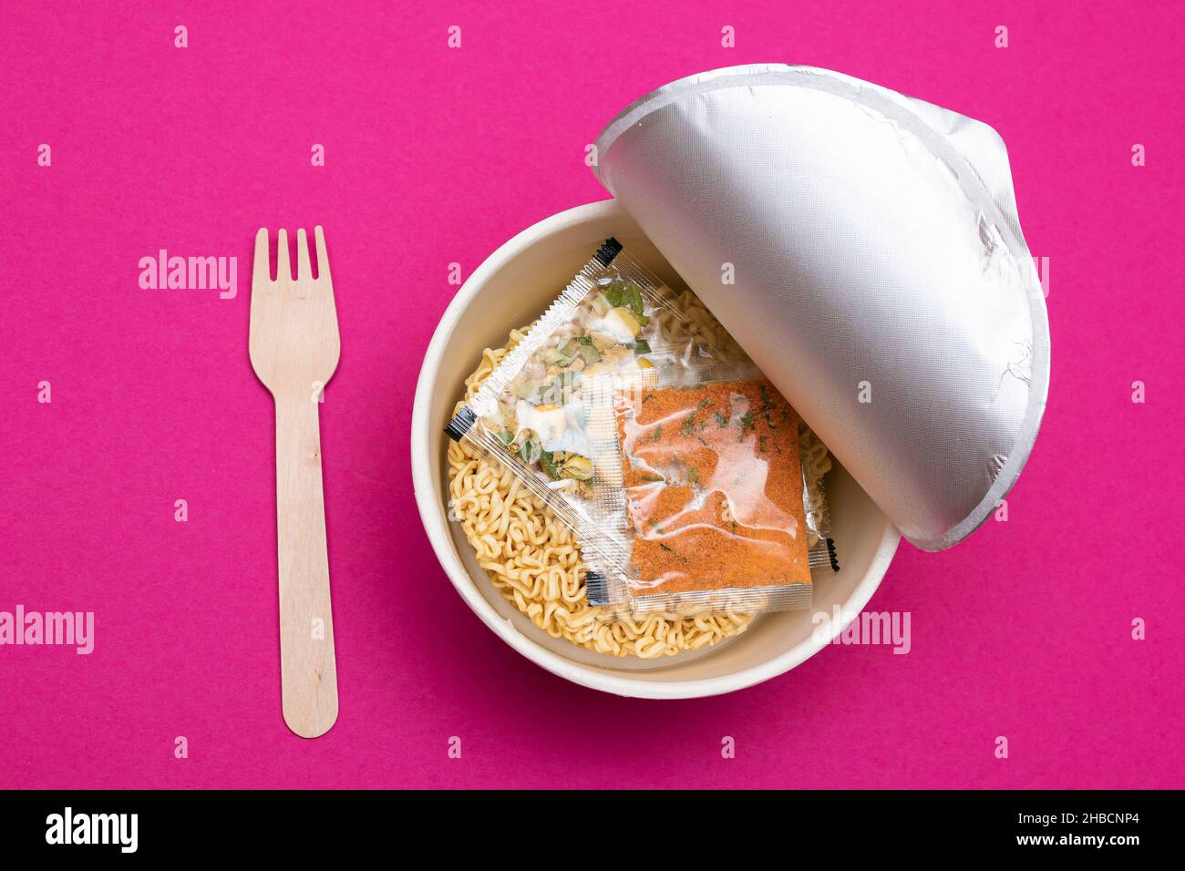 Forfait ouvert avec nouilles instantanées non cuites sur fond rose ...