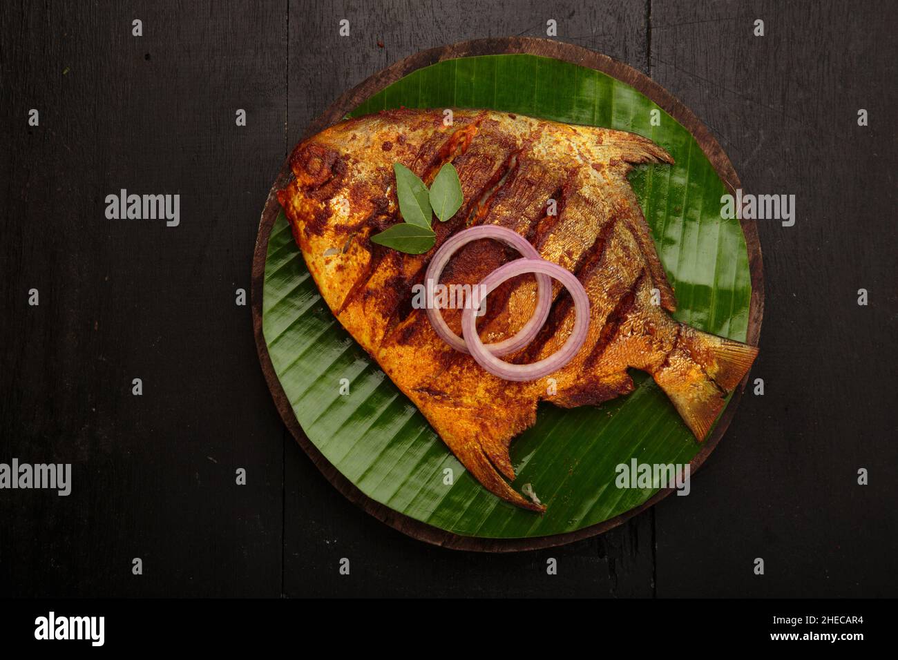 Poisson frite, disposé dans une base ronde en bois bordée de feuille de ...
