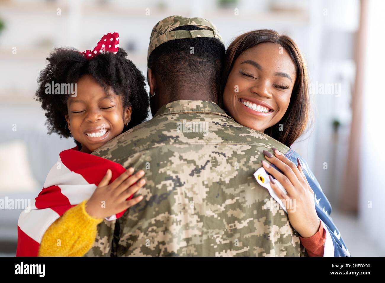 Concept de soins à domicile.Soldat américain qui embrasse sa femme et sa fille après son retour ...