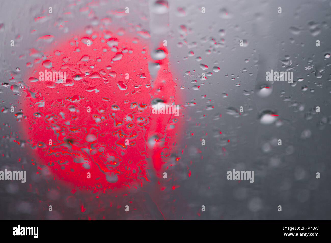 Cercle ou tache rouge lumineux flou vu à travers un verre avec des ...