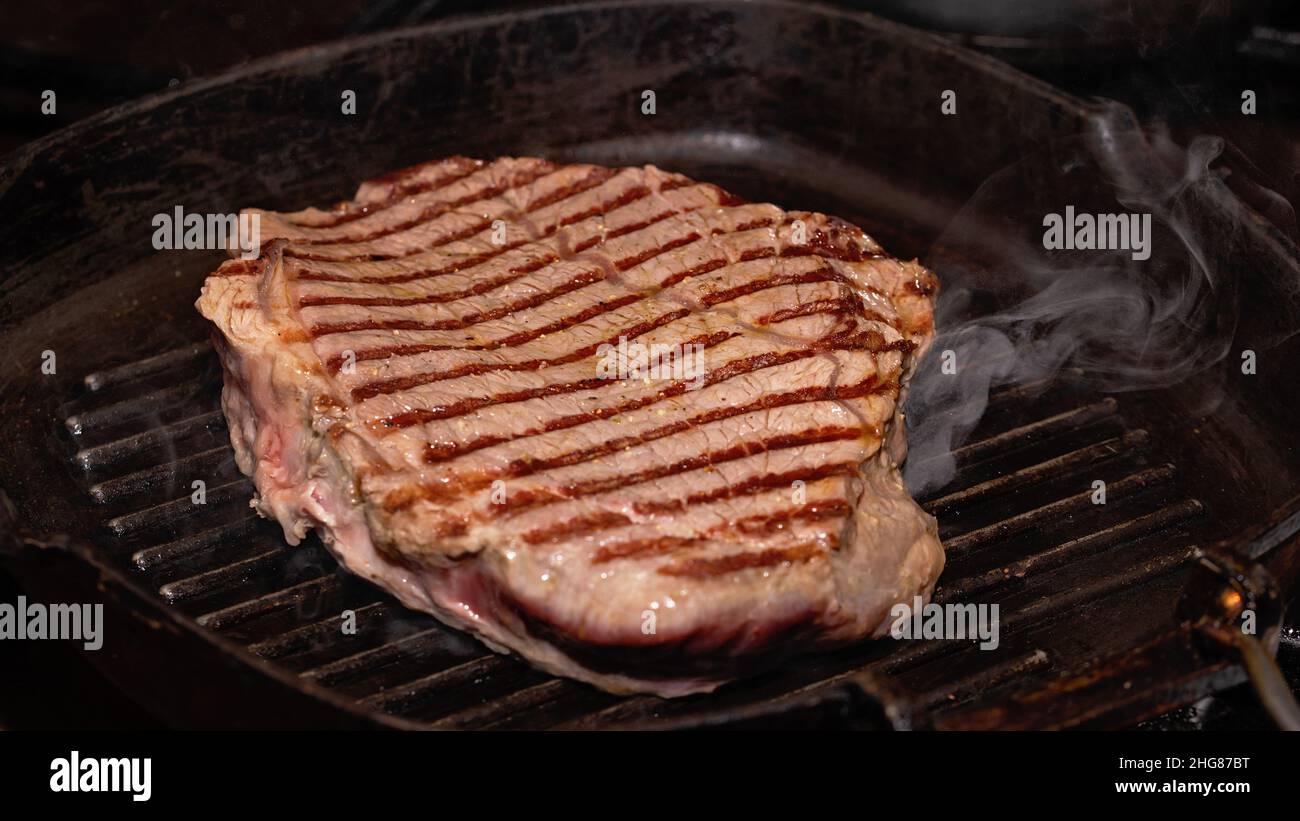Viande de bœuf grillée en gros plan dans une poêle à frire striée en ...