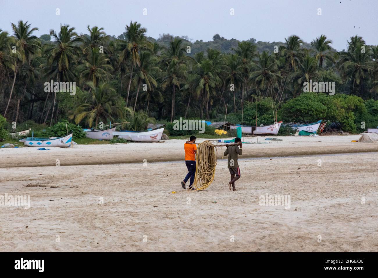 Deux pêcheurs transportant du matériel de pêche sur leur dos à la plage ...