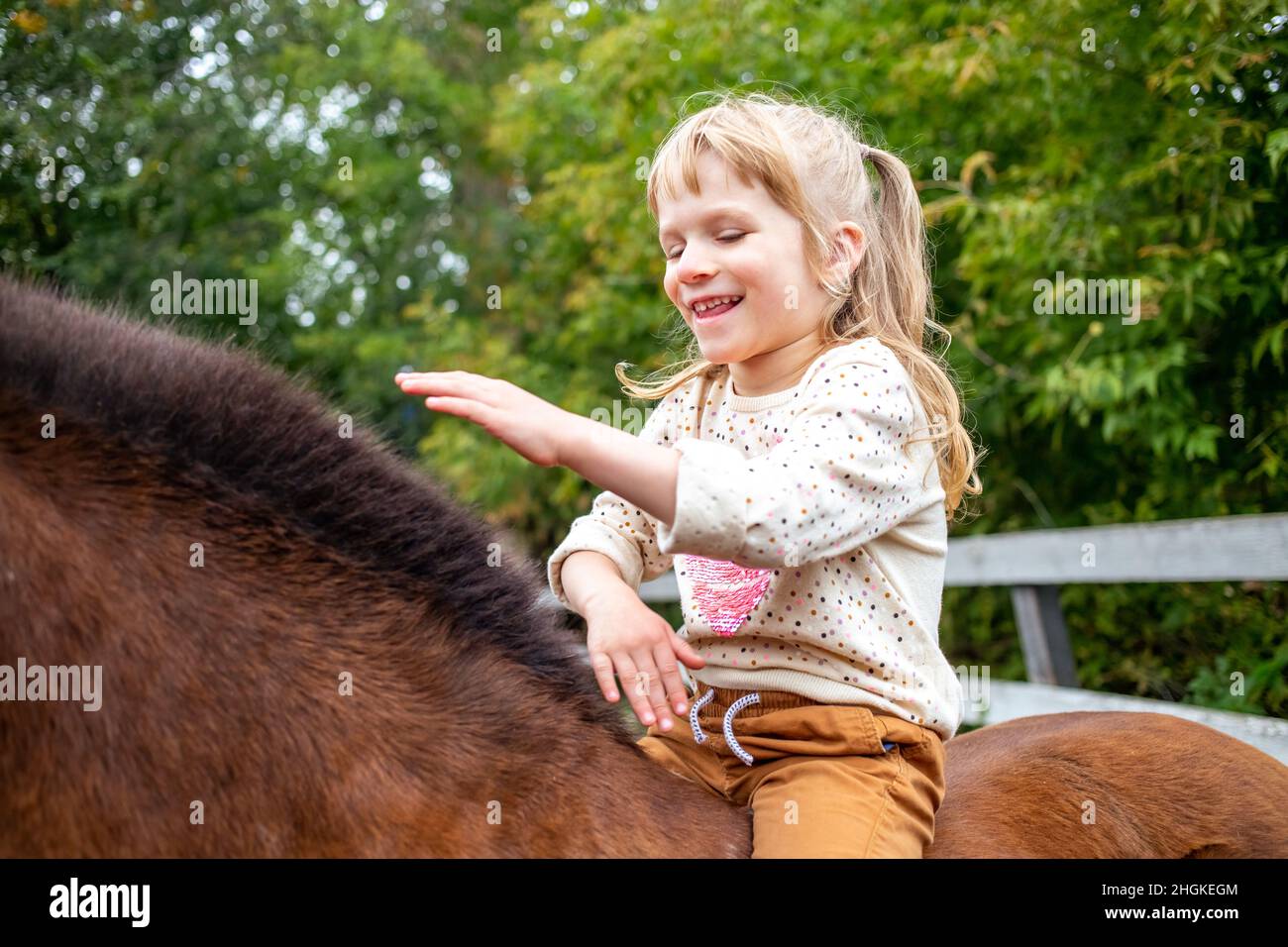 une fille gaie est assise et fait un cheval sur la manie Photo Stock - Alamy