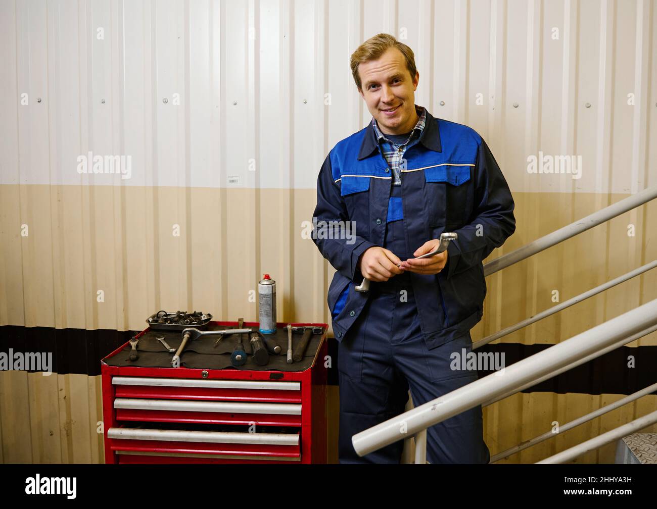 Portrait d'un beau homme caucasien, mécanicien de garage, technicien tenant une clé et regardant ...