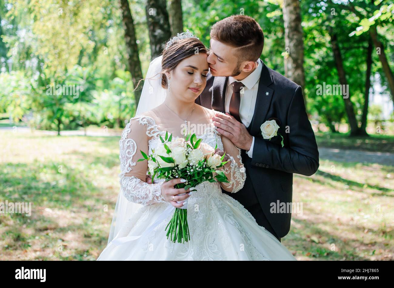 La mariée et le marié marchent dans le parc en été, embrassant.Les ...