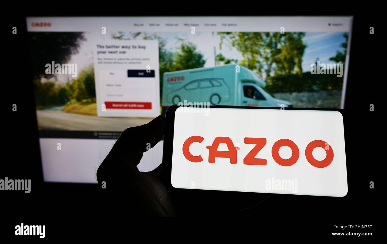 Personne tenant un téléphone mobile avec le logo de la compagnie de vente de voitures ...