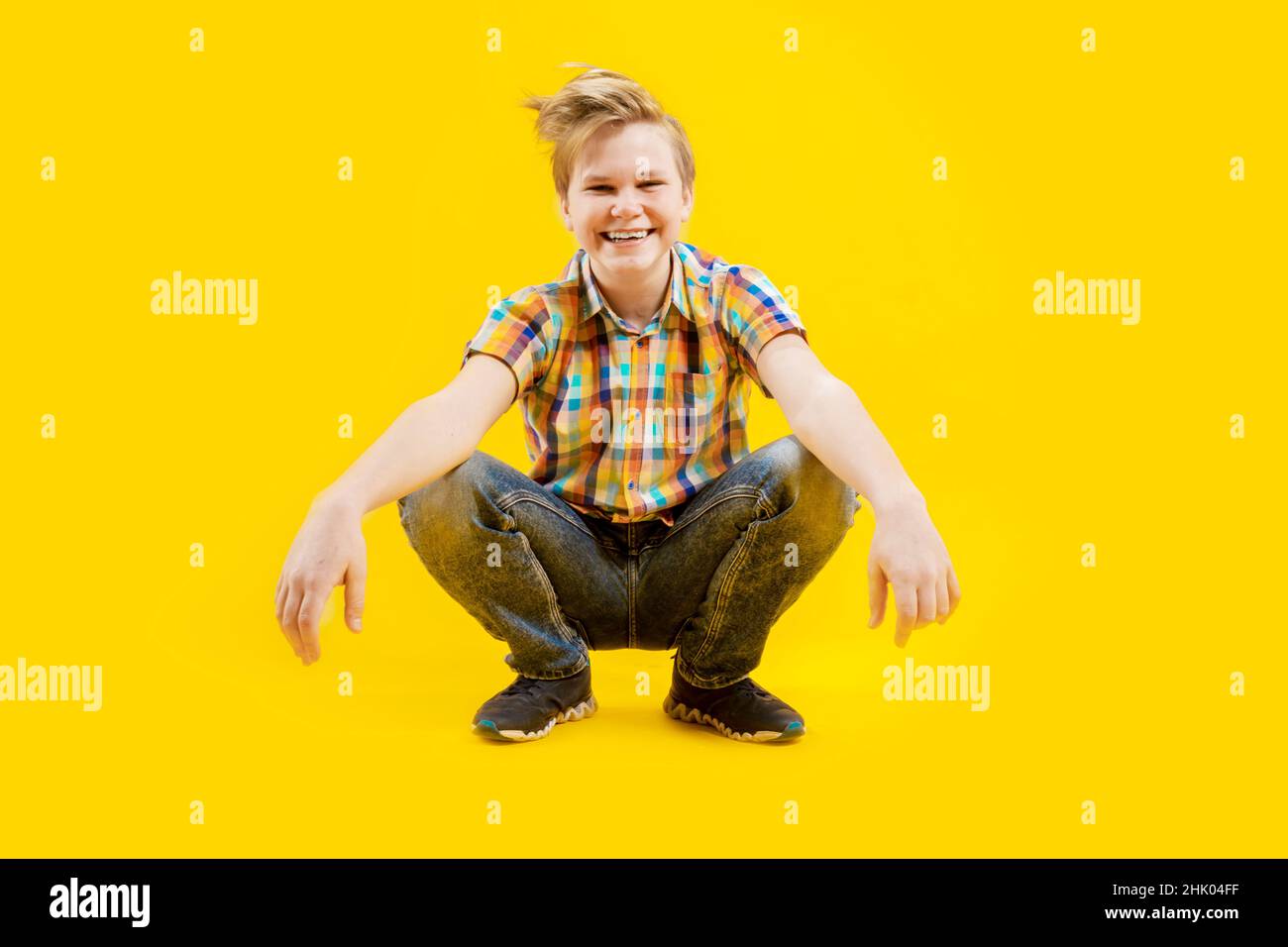 Un adorable garçon en train de rire est assis avec un visage drôle et ...