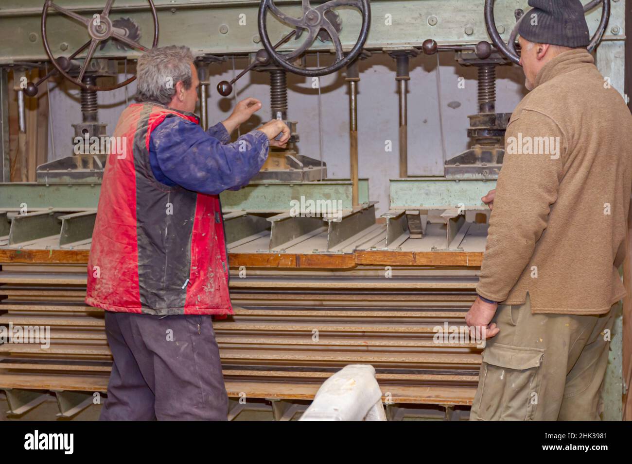 Une équipe de travailleurs presse à l'aide d'une presse, tourne le ...