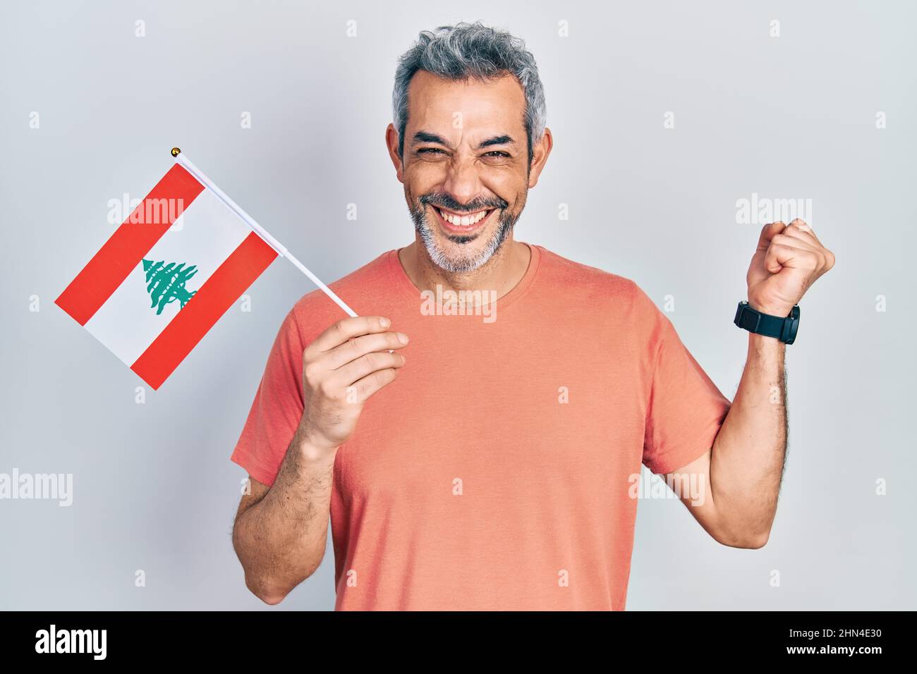 Beau homme d'âge moyen aux cheveux gris tenant le drapeau libanais ...