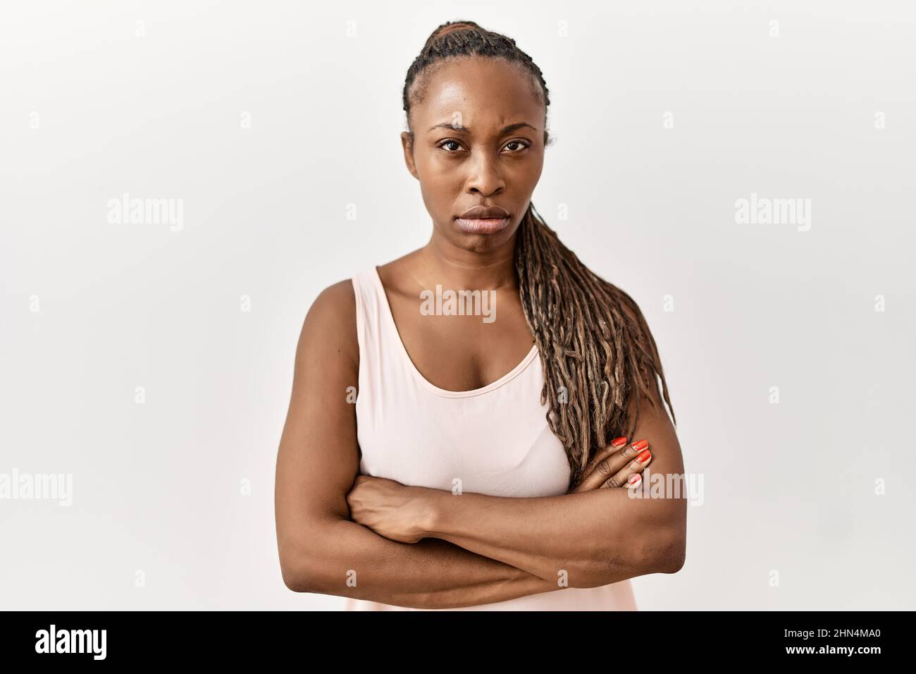 Femme noire avec des tresses debout sur un fond isolé sceptique et nerveux, désapprouvant l ...