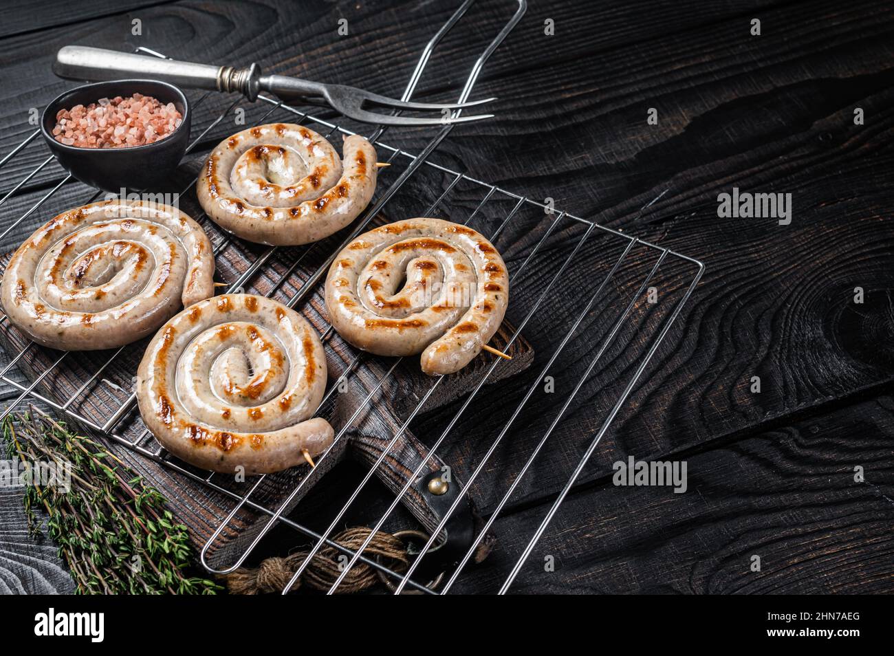Barbecue de saucisses de viande de porc en spirale grillées sur un grill. Arrière-plan noir. Vue ...
