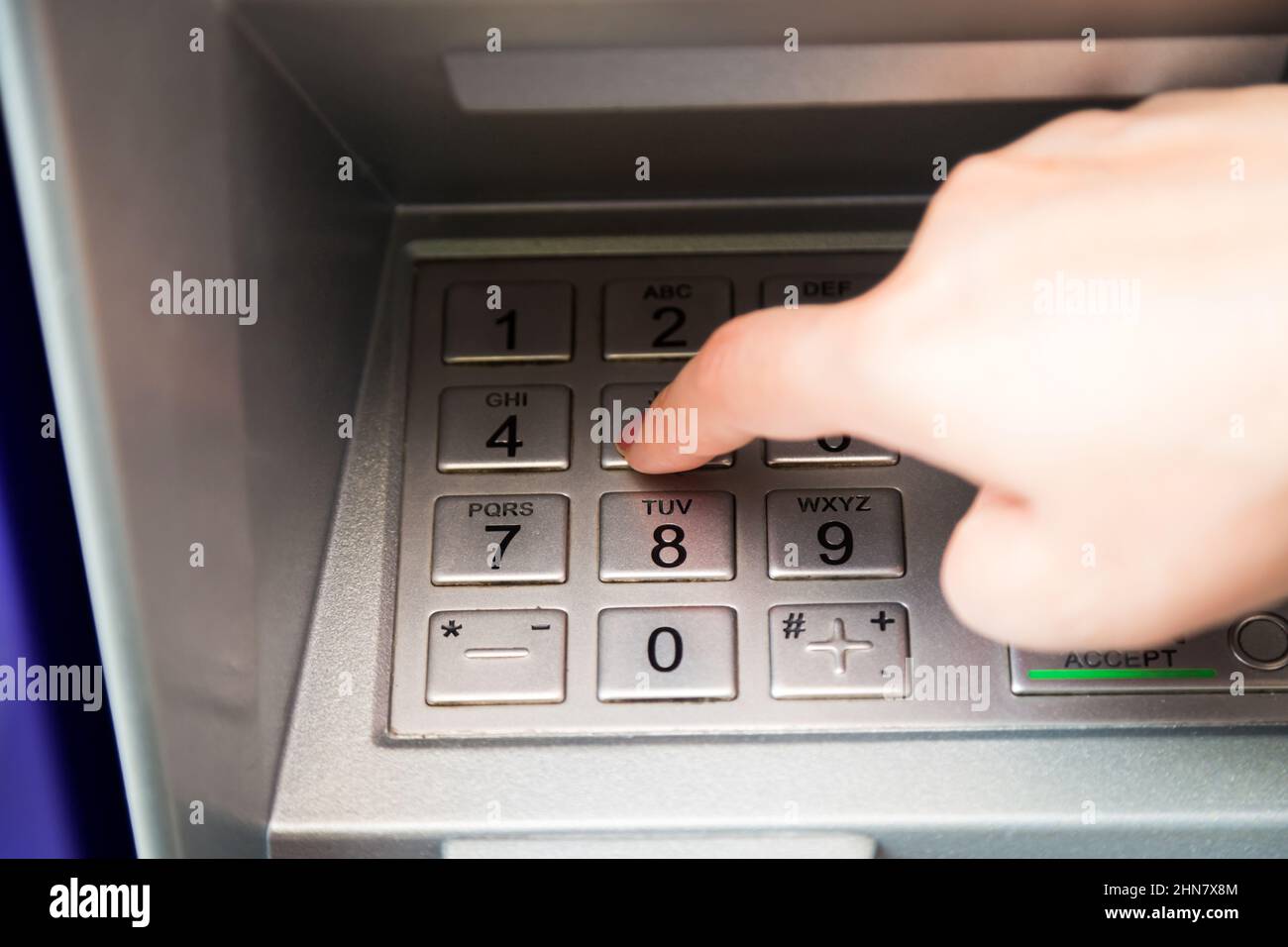 Gros plan de la main en entrant le code PIN au guichet automatique pour ...