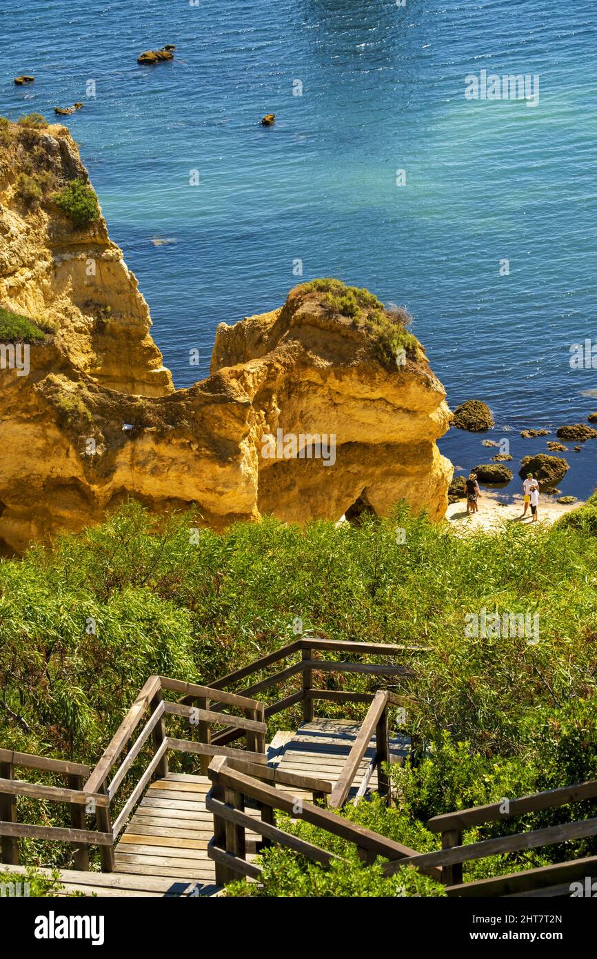 rocher jaune doré et falaise et passerelle en bois vers la belle plage ...