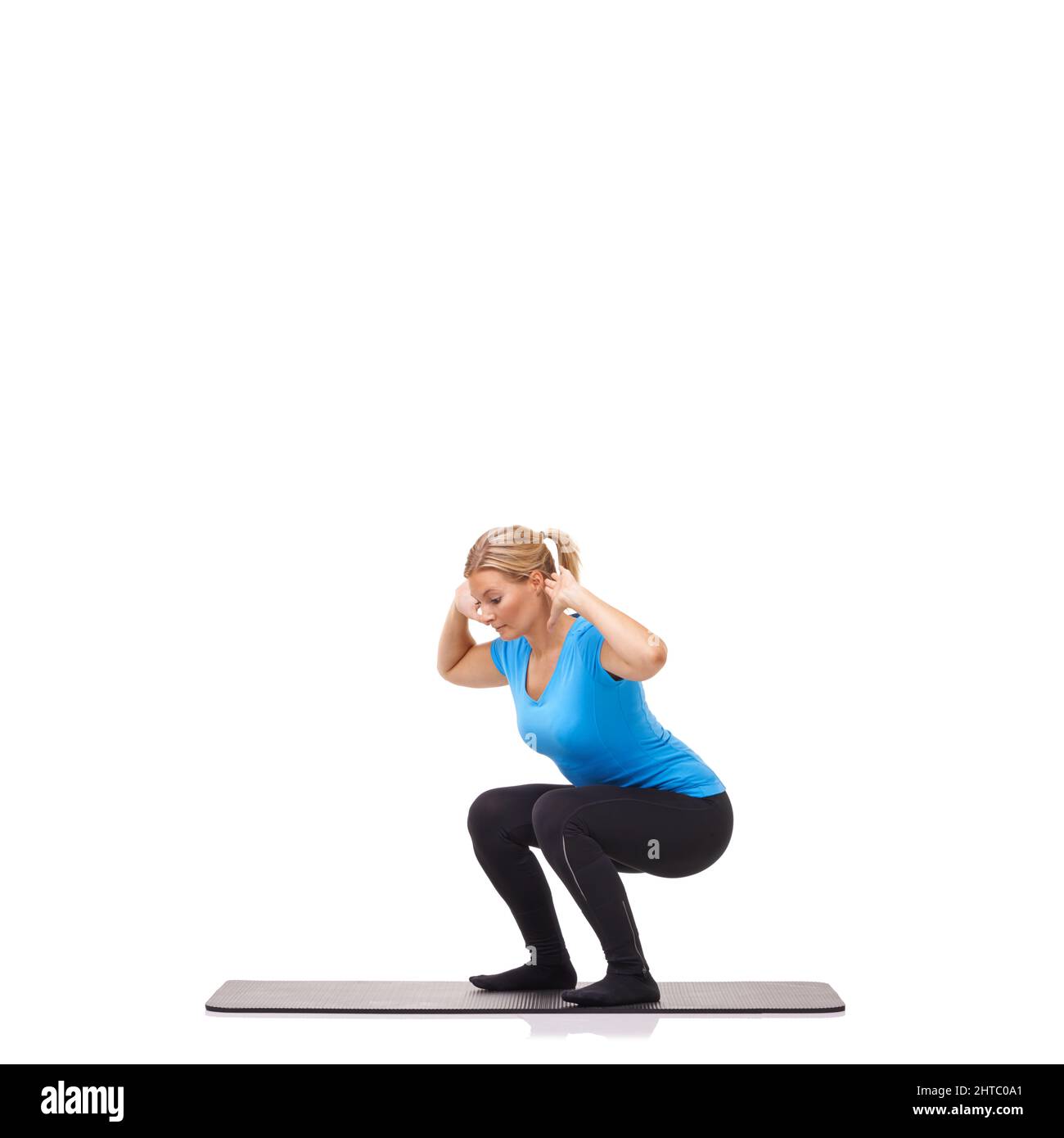 Faire des squats avec les bras relevés. Une jeune femme qui se croise ...