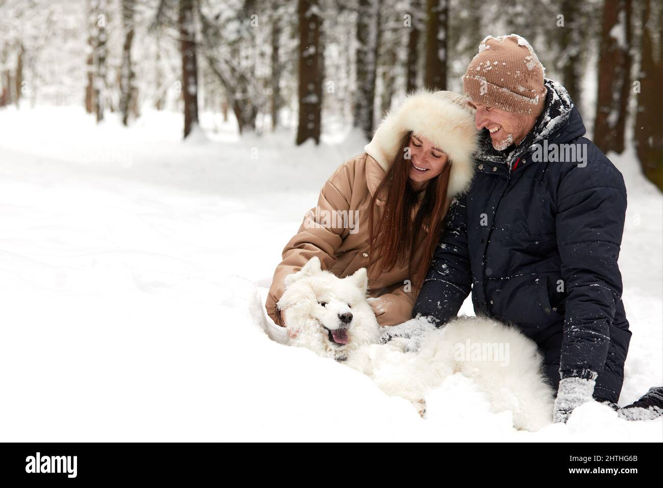 Joyeux jeune couple en hiver jouant avec husky siberien à la purée et s'amuser dans la forêt de ...
