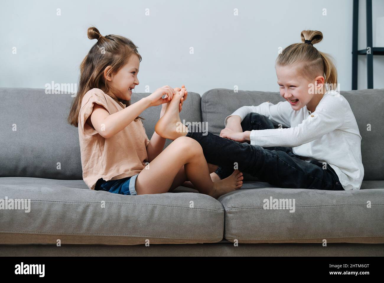 Petite fille essayant de chatouiller le pied du garçon, ils rient tous ...