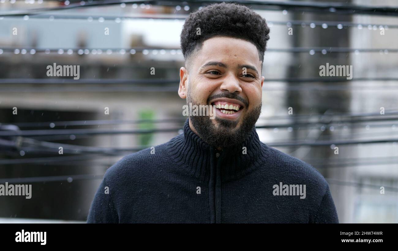 Un jeune brésilien debout dans la bruine souriant au visage du portrait ...