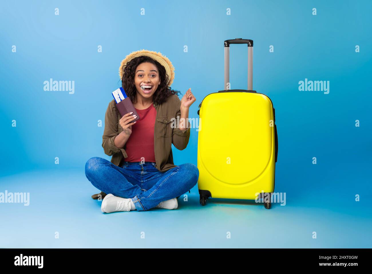 Jeune femme noire excitée avec une valise lumineuse, un passeport et un ...
