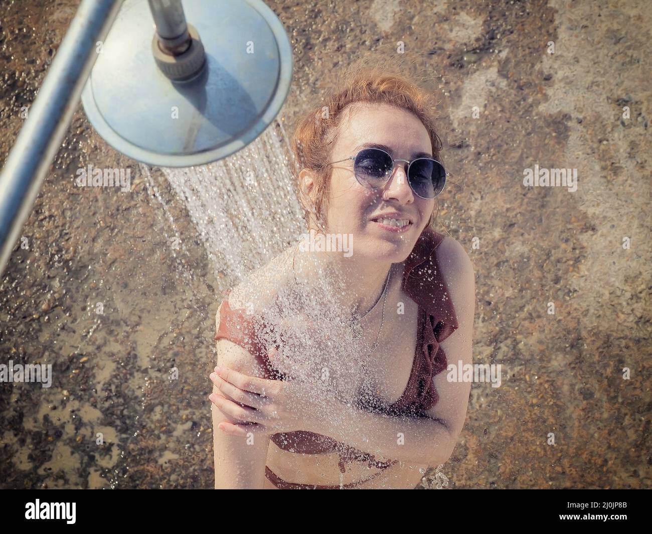 La Fille En Lunettes De Soleil Et Un Bikini Se Lave Sous La Douche à L