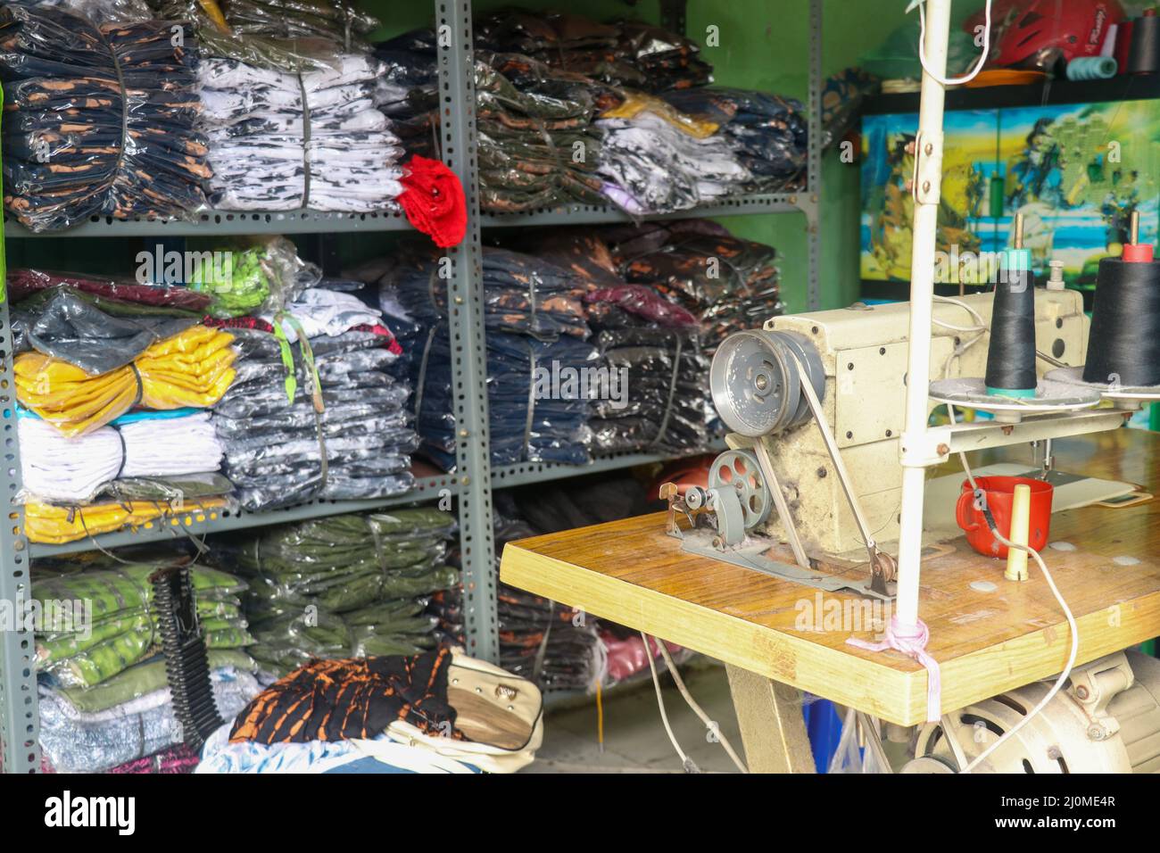 machine à coudre dans un atelier de tailleur avec des piles de tissus ...