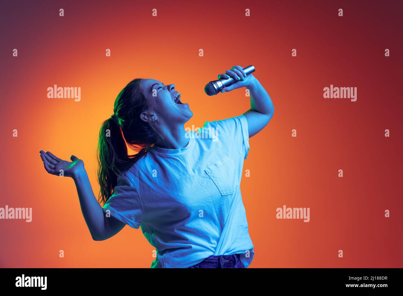 Portrait d'une jeune fille qui chante avec émotion dans un microphone ...