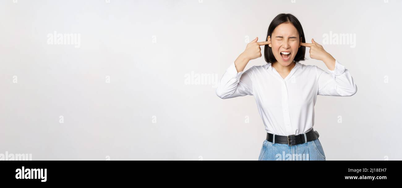 Une femme asiatique agacée se sente gêné par un bruit fort et ennuyeux ...
