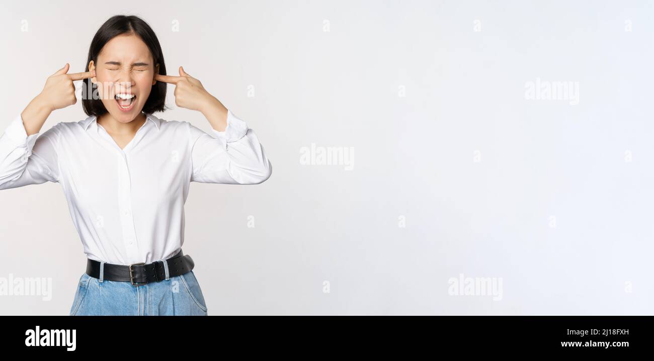 Une femme asiatique agacée se sente gêné par un bruit fort et ennuyeux ...