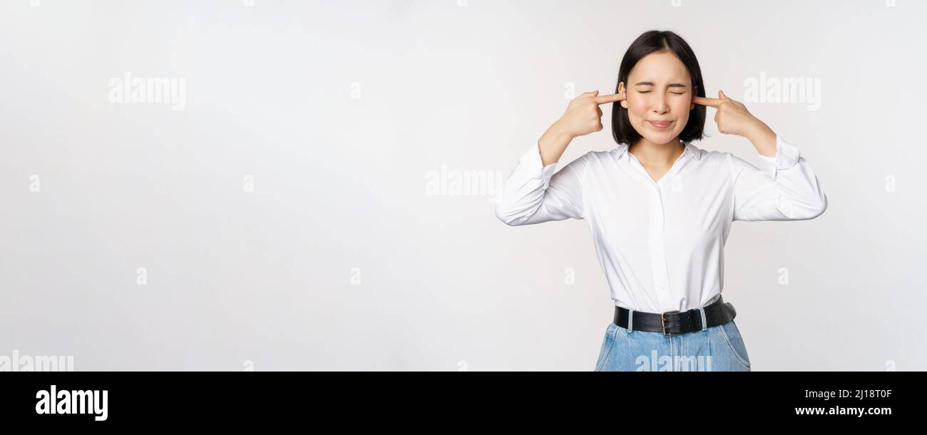 Une femme asiatique agacée se sente gêné par un bruit fort et ennuyeux ...