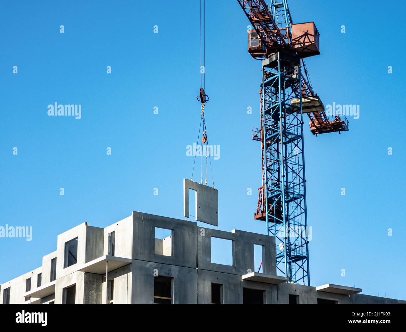 La grue à tour livre une dalle de béton sur un chantier de construction ...