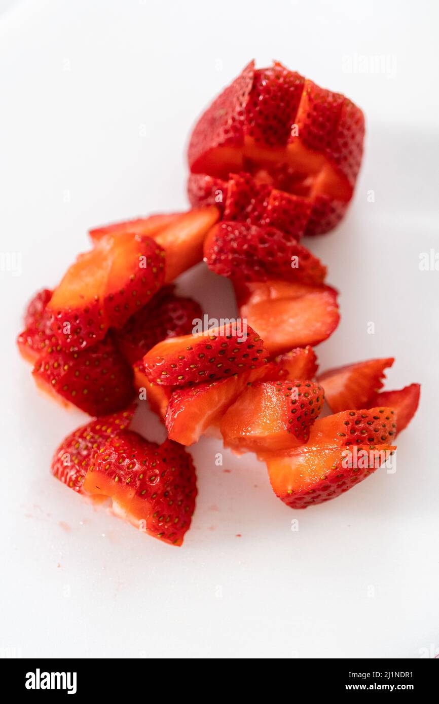 Couper des fraises fraîches sur une planche à découper blanche pour ...