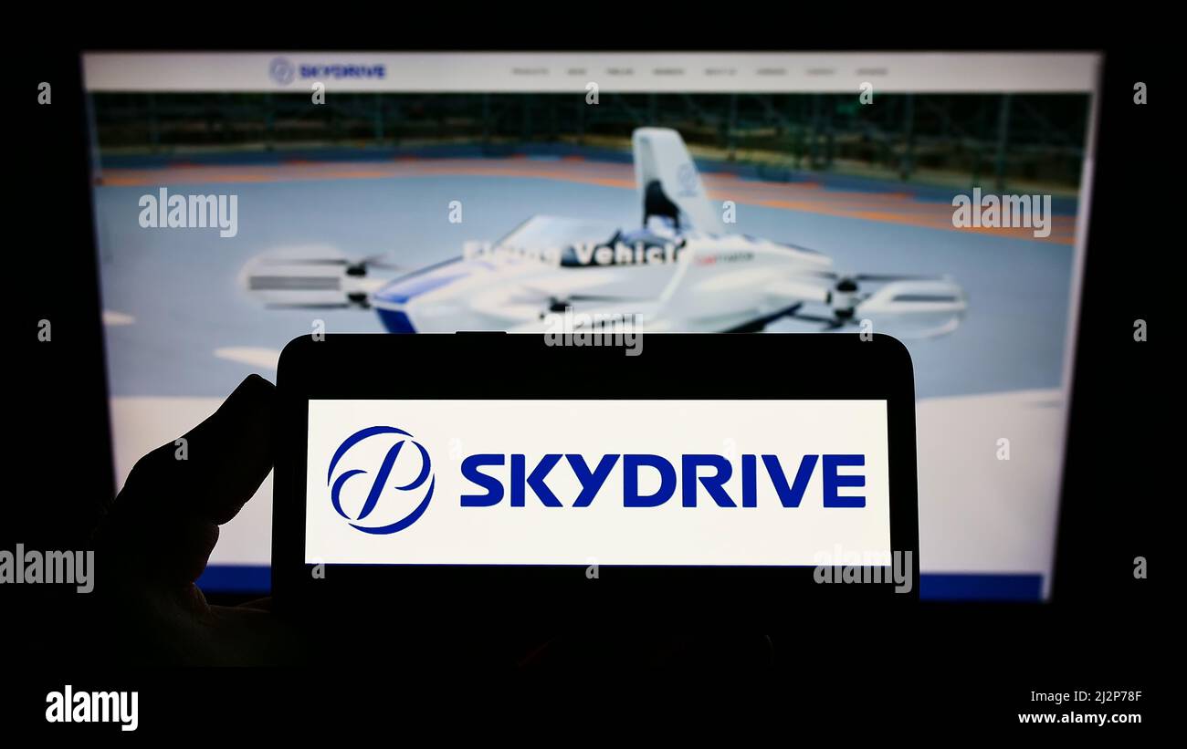 Personne tenant un smartphone avec le logo de la compagnie aérienne japonaise SkyDrive Inc. À l ...